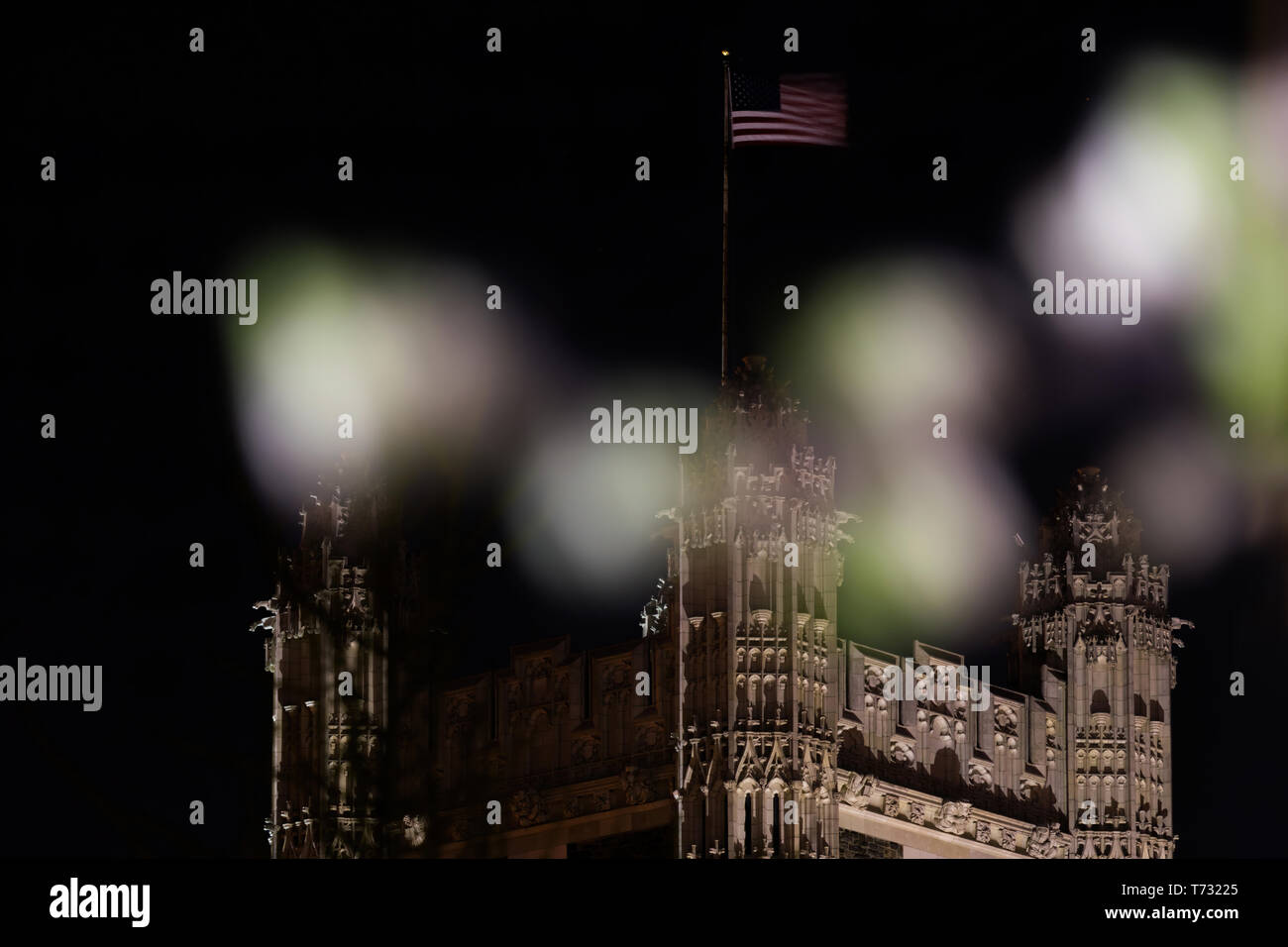 American flag waves high above a tower with gothic architecture, with ...