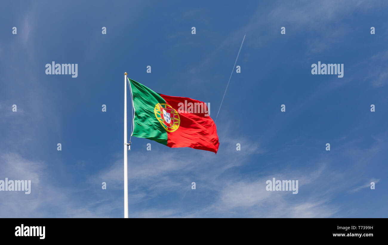 Beautiful large Portuguese flag waving in the wind against blue sky ...