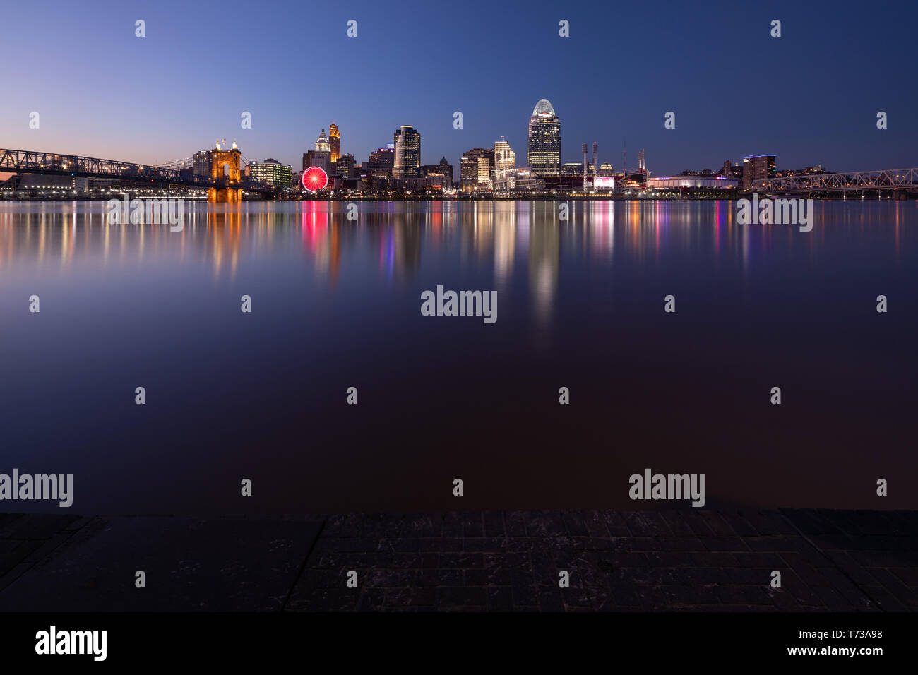 The sun sets in a clear blue sky over Cincinnati as city lights emerge ...