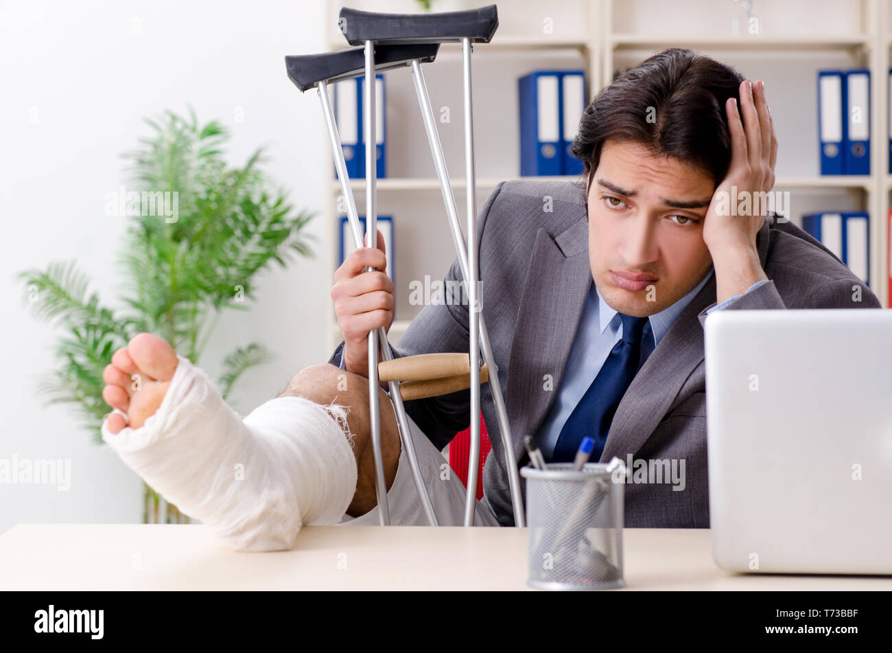 Leg injured employee working in the office Stock Photo - Alamy