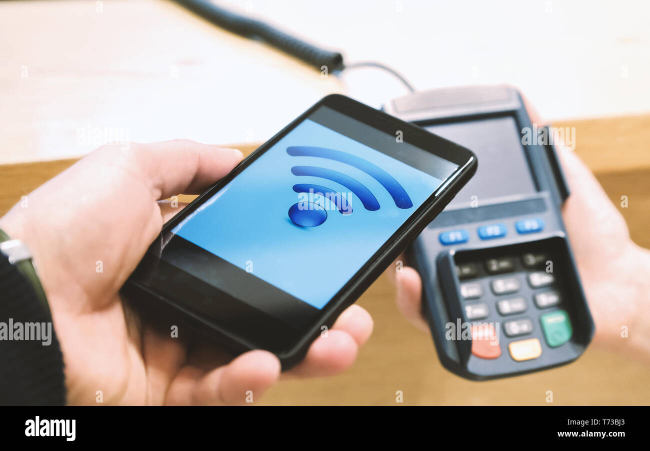 Pay by smartphone through the terminal. Man with smartphone mobile ...