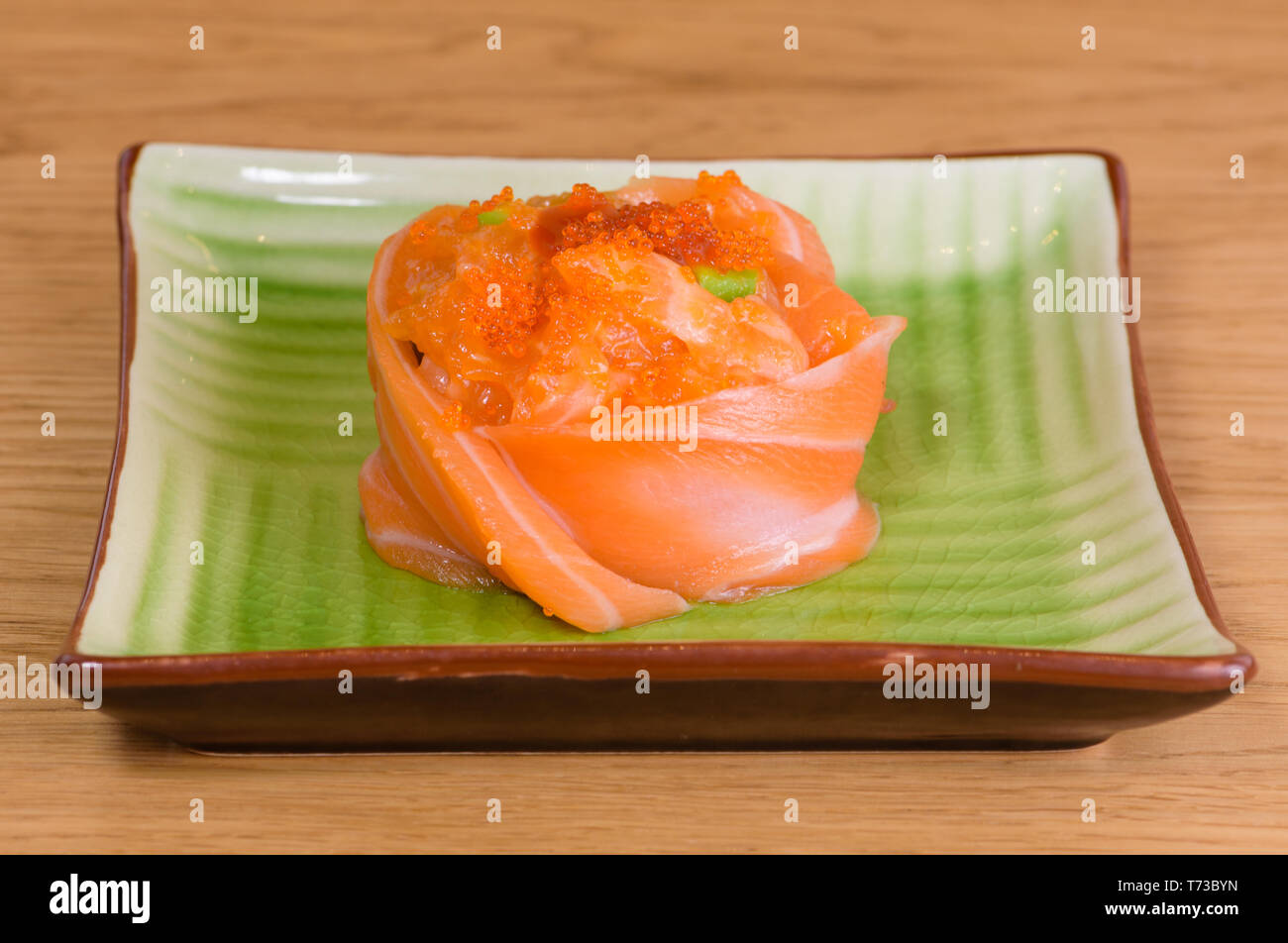 salmon sashimi with caviar and avocado served on a plate, seen from 45 ...