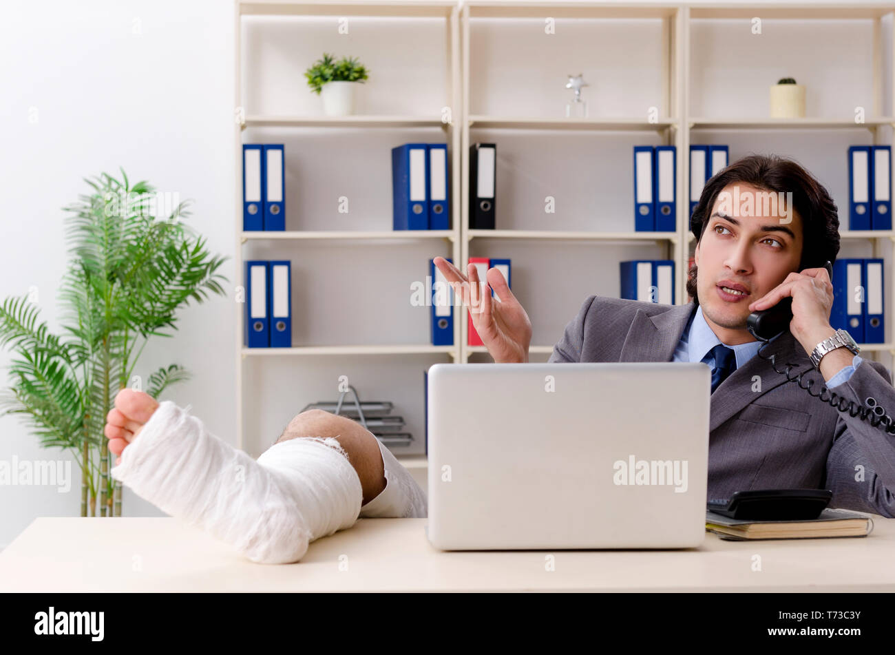Leg injured employee working in the office Stock Photo - Alamy