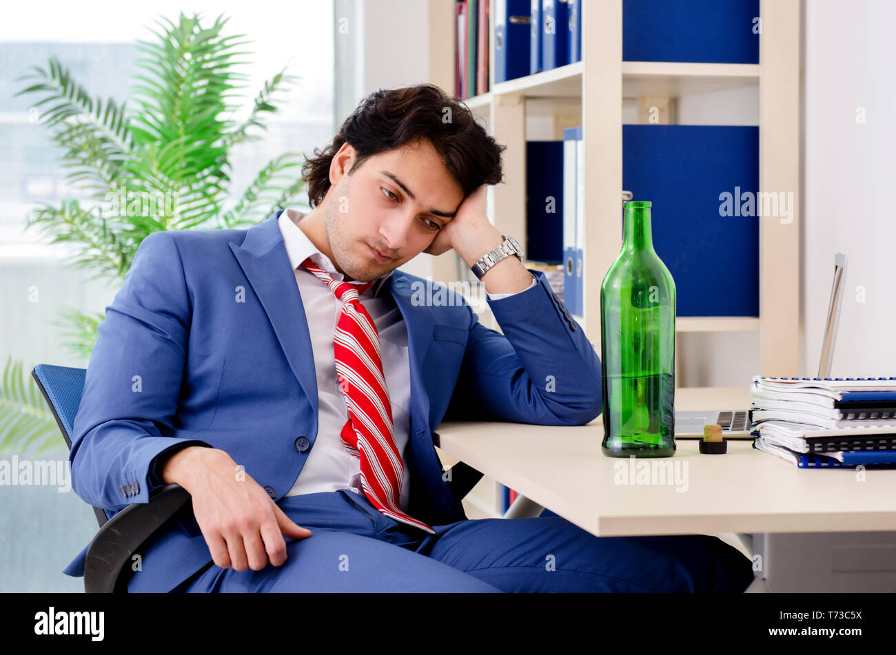 Young businessman employee drinking in the office Stock Photo - Alamy