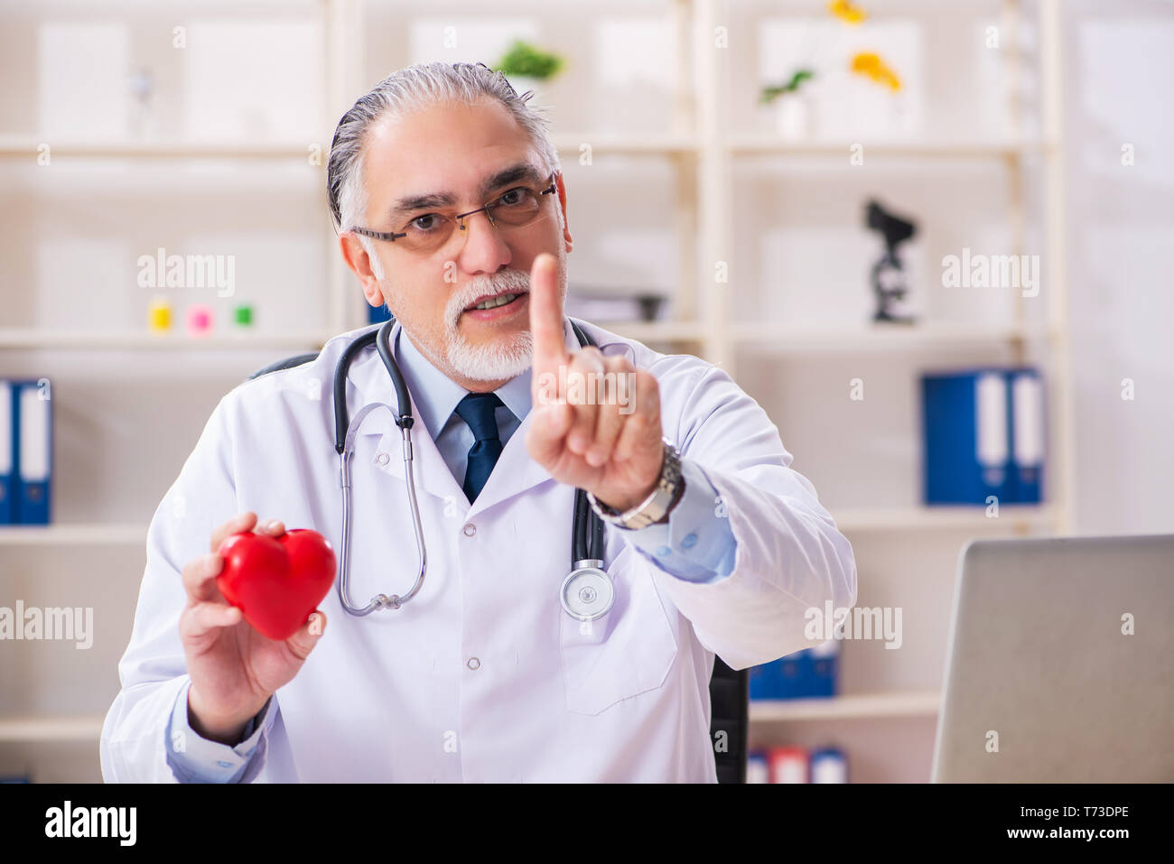 Aged male doctor cardiologist with heart model Stock Photo - Alamy