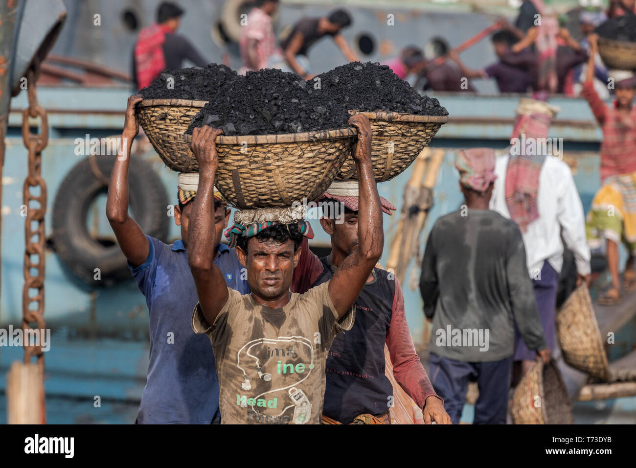 Male & Female dock workers are seen as they unload coal with bamboo ...