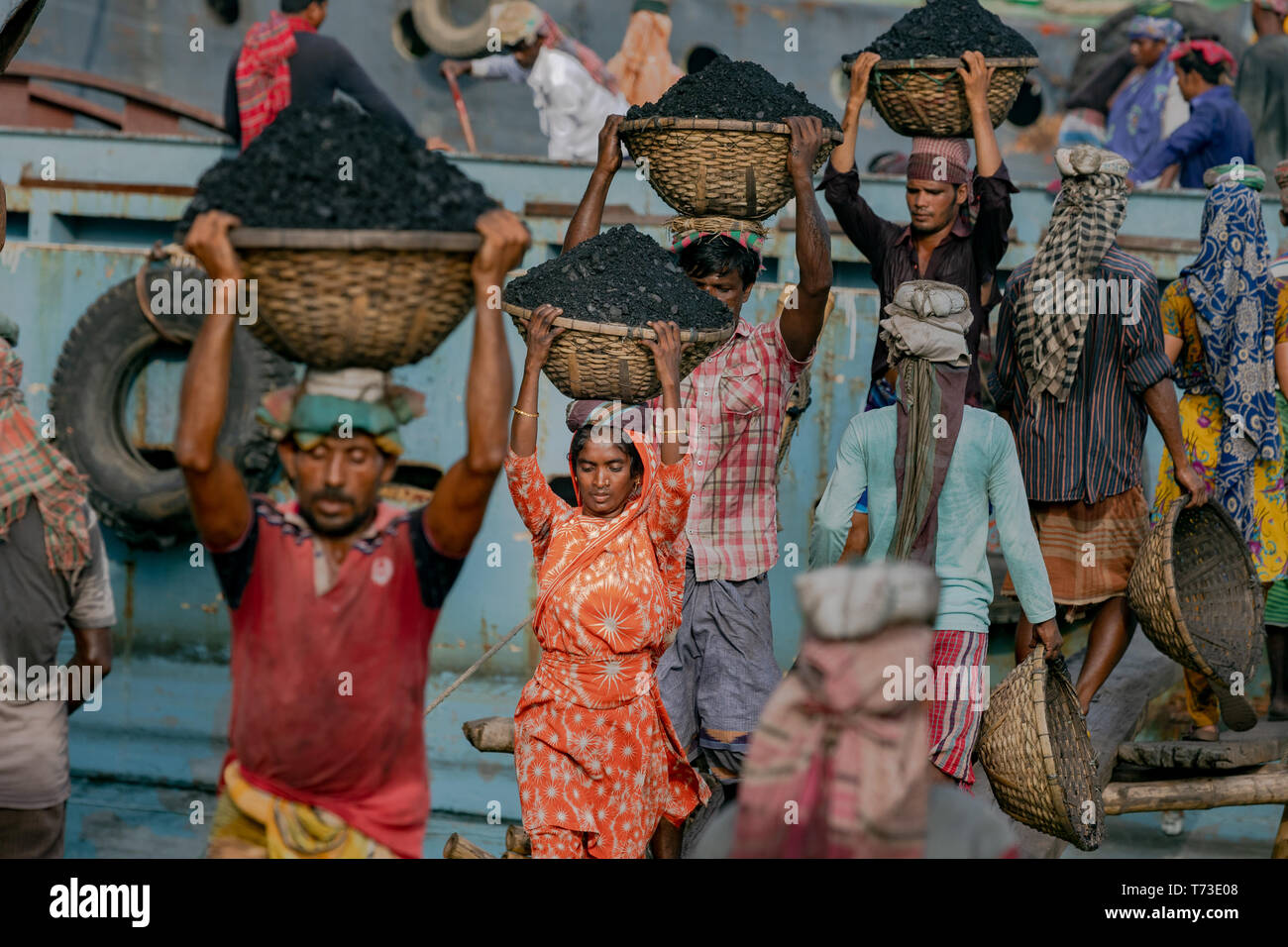 Male & Female dock workers are seen as they unload coal with bamboo ...