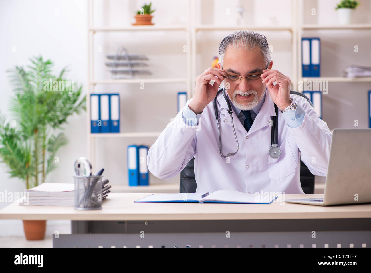 Aged male doctor working in the clinic Stock Photo - Alamy