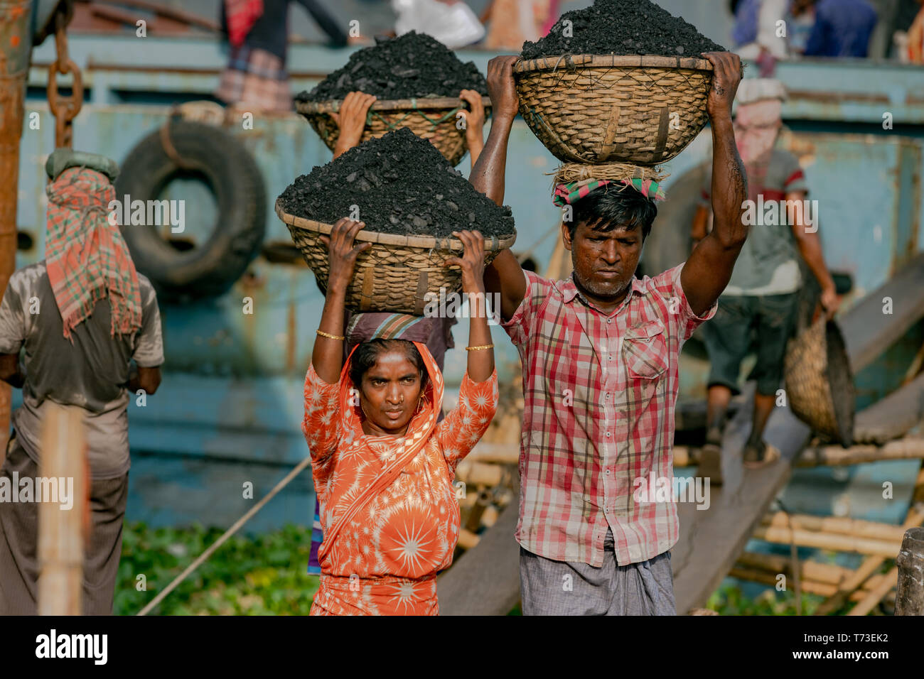 Male & Female dock workers are seen as they unload coal with bamboo ...