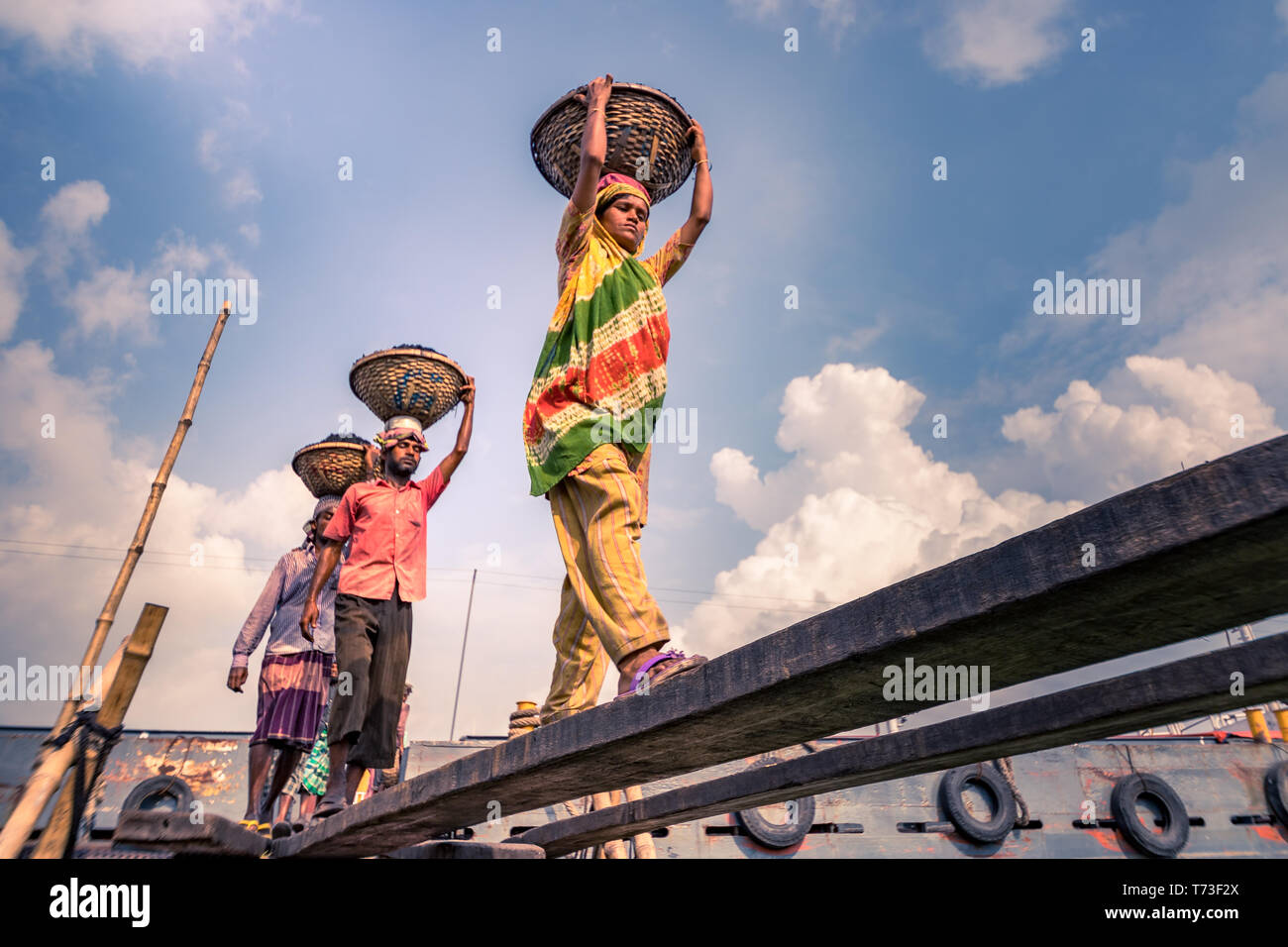 Male & Female dock workers are seen as they unload coal with bamboo ...