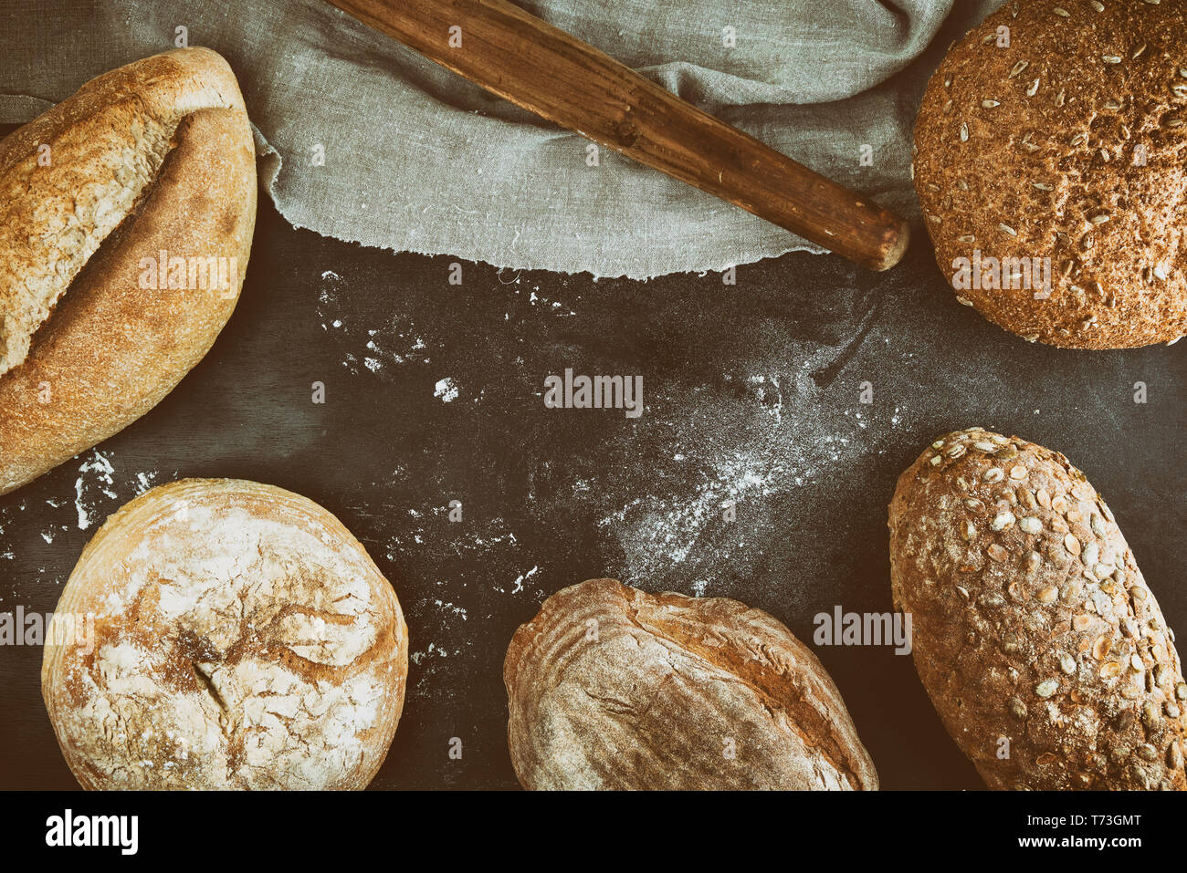 baked various loaves of bread on a black background, empty space in the ...