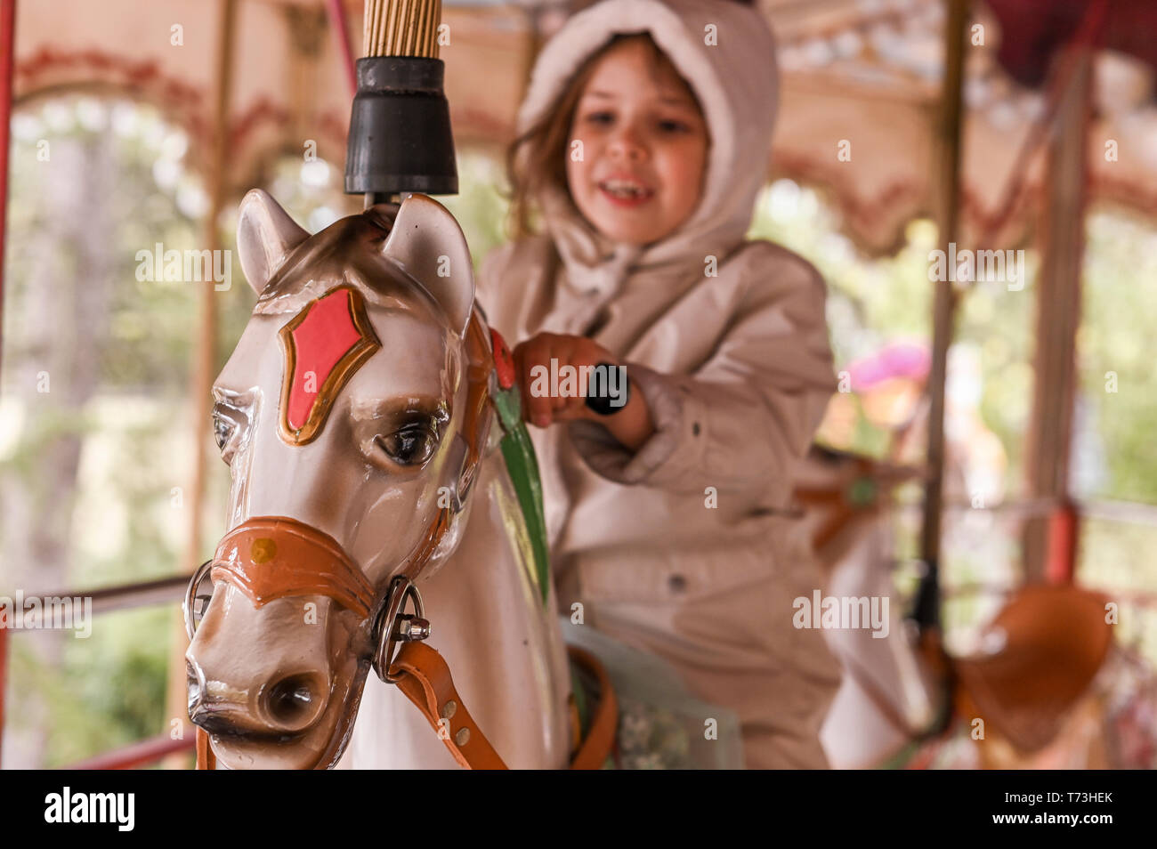 Little girl rides a carousel in an amusement park. Happy child Stock ...