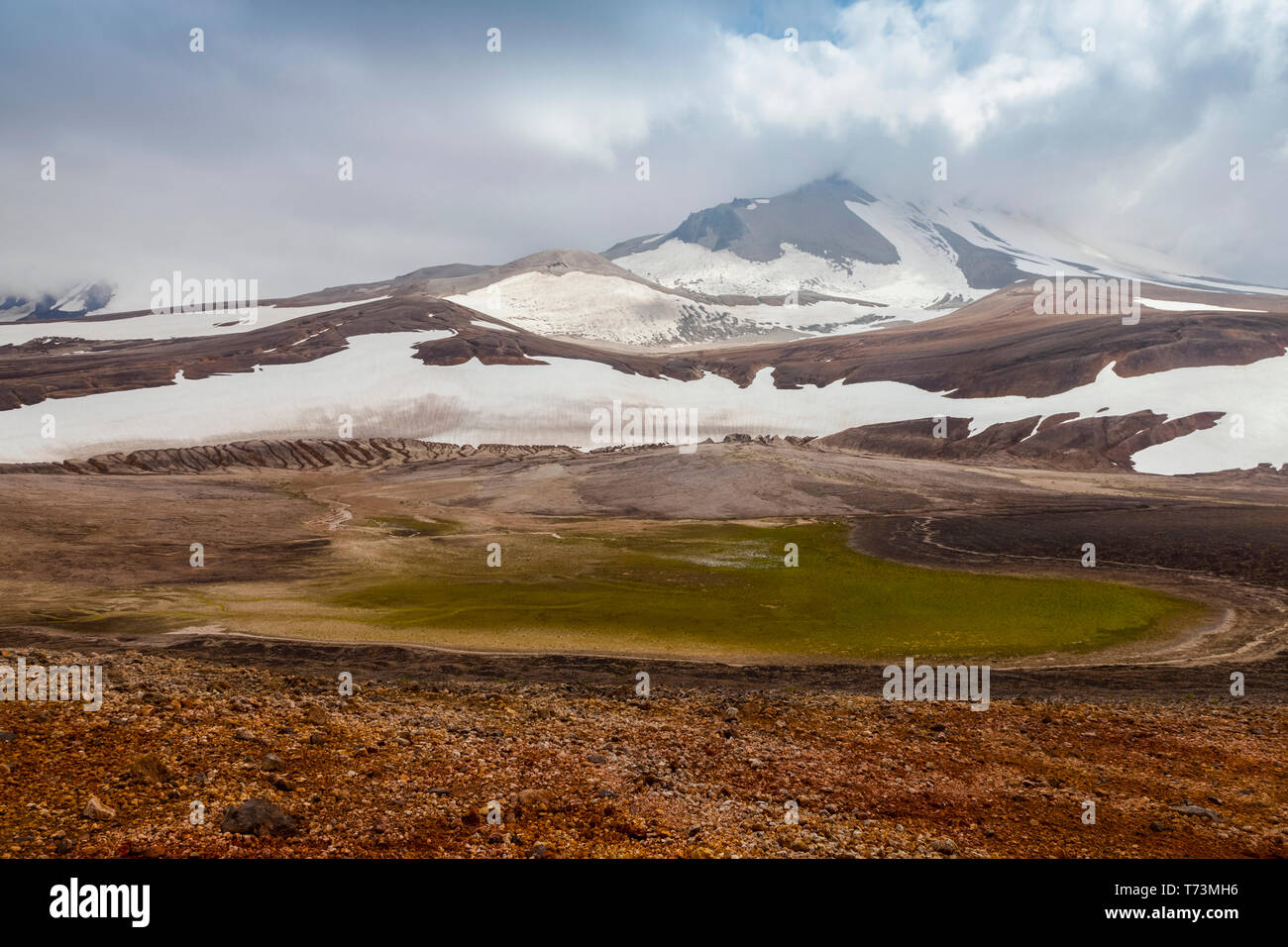 Rainbow-coloured pumice in foreground viewing Mount Katmai in ...