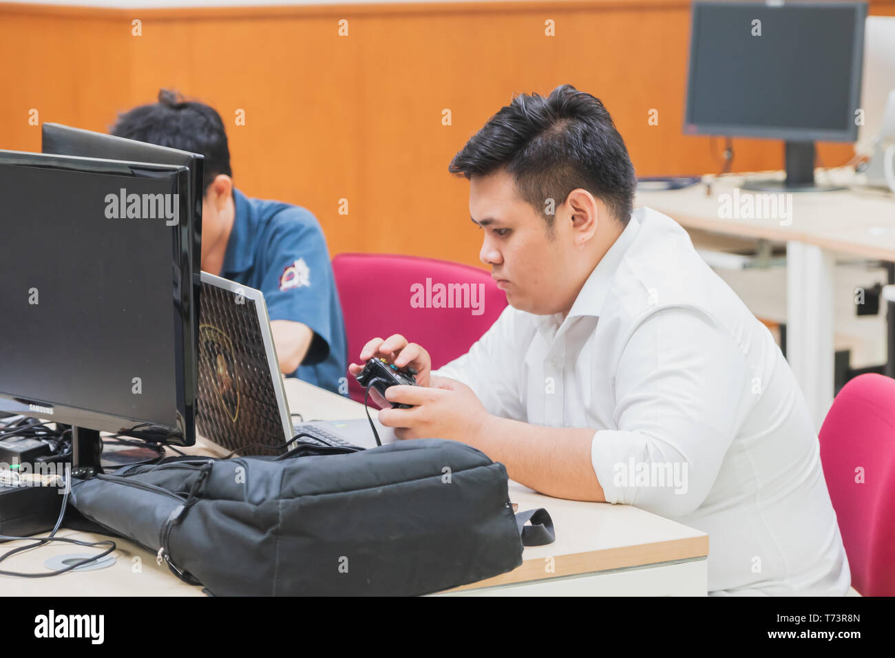 Asian University Student playing game on his laptop during a computer ...