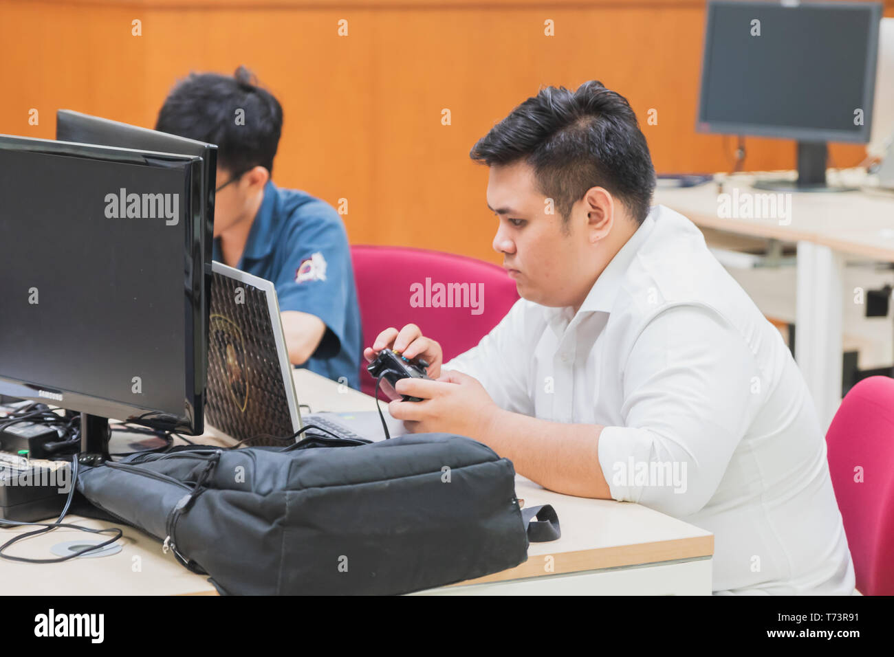 Asian University Student playing game on his laptop during a computer ...