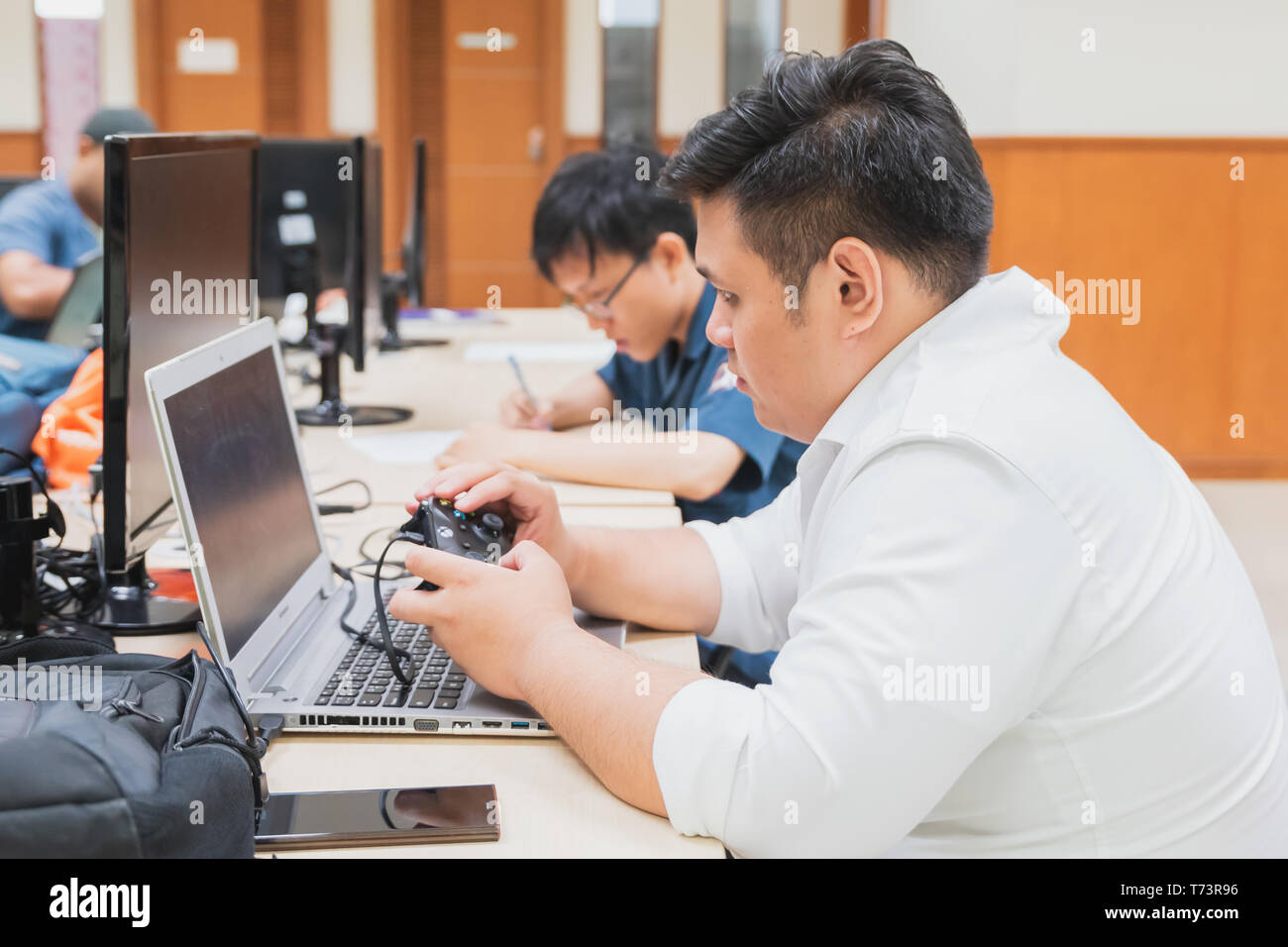 Asian University Student playing game on his laptop during a computer ...