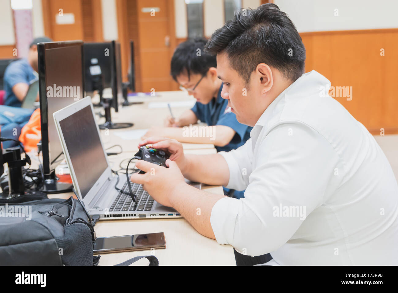 Asian University Student playing game on his laptop during a computer ...