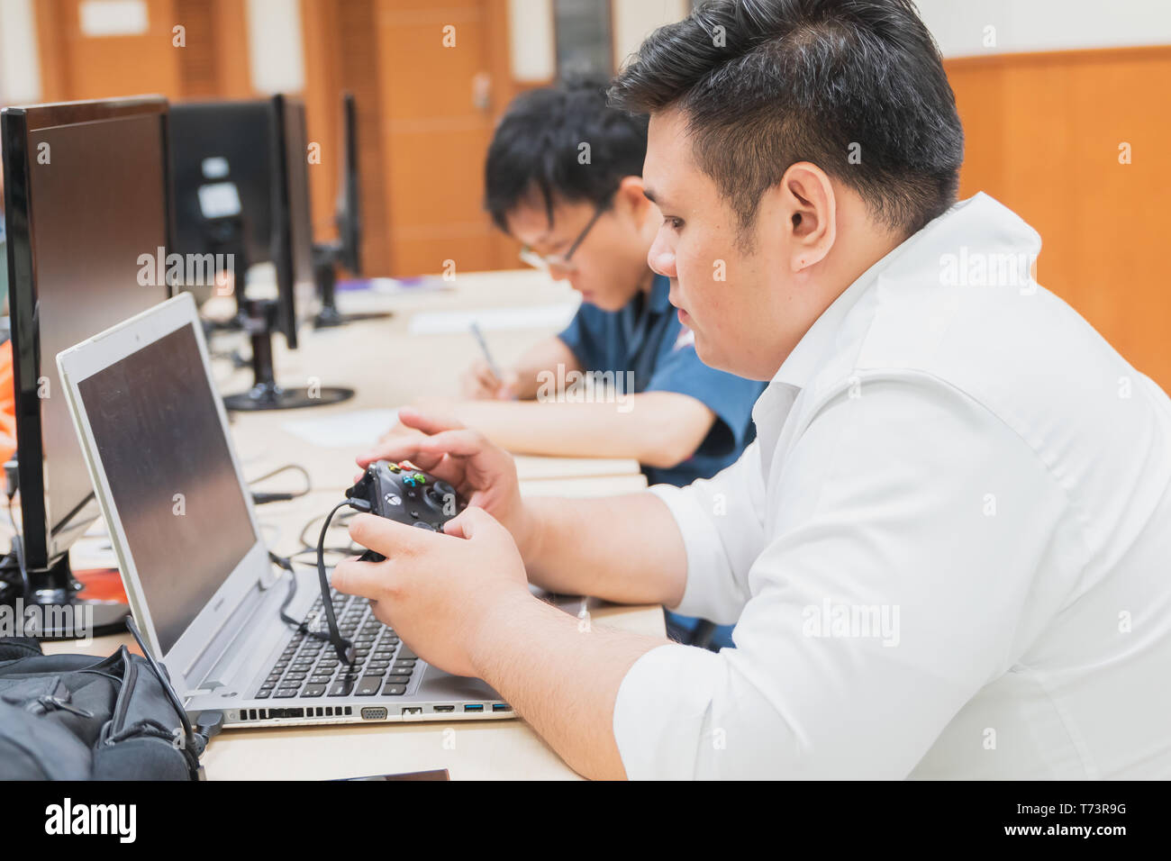 Asian University Student playing game on his laptop during a computer ...