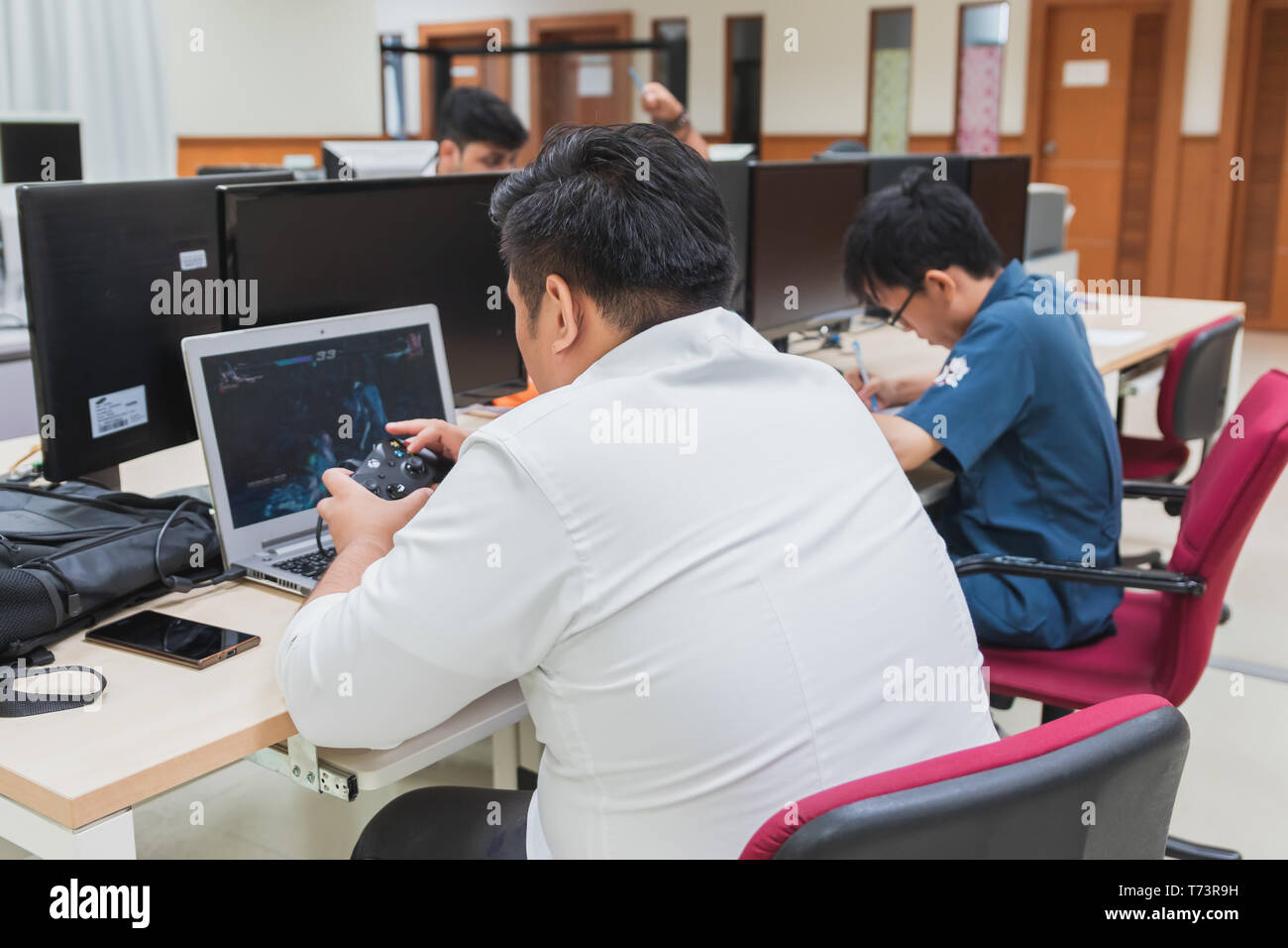 Back of Asian university student playing game in the classroom during ...