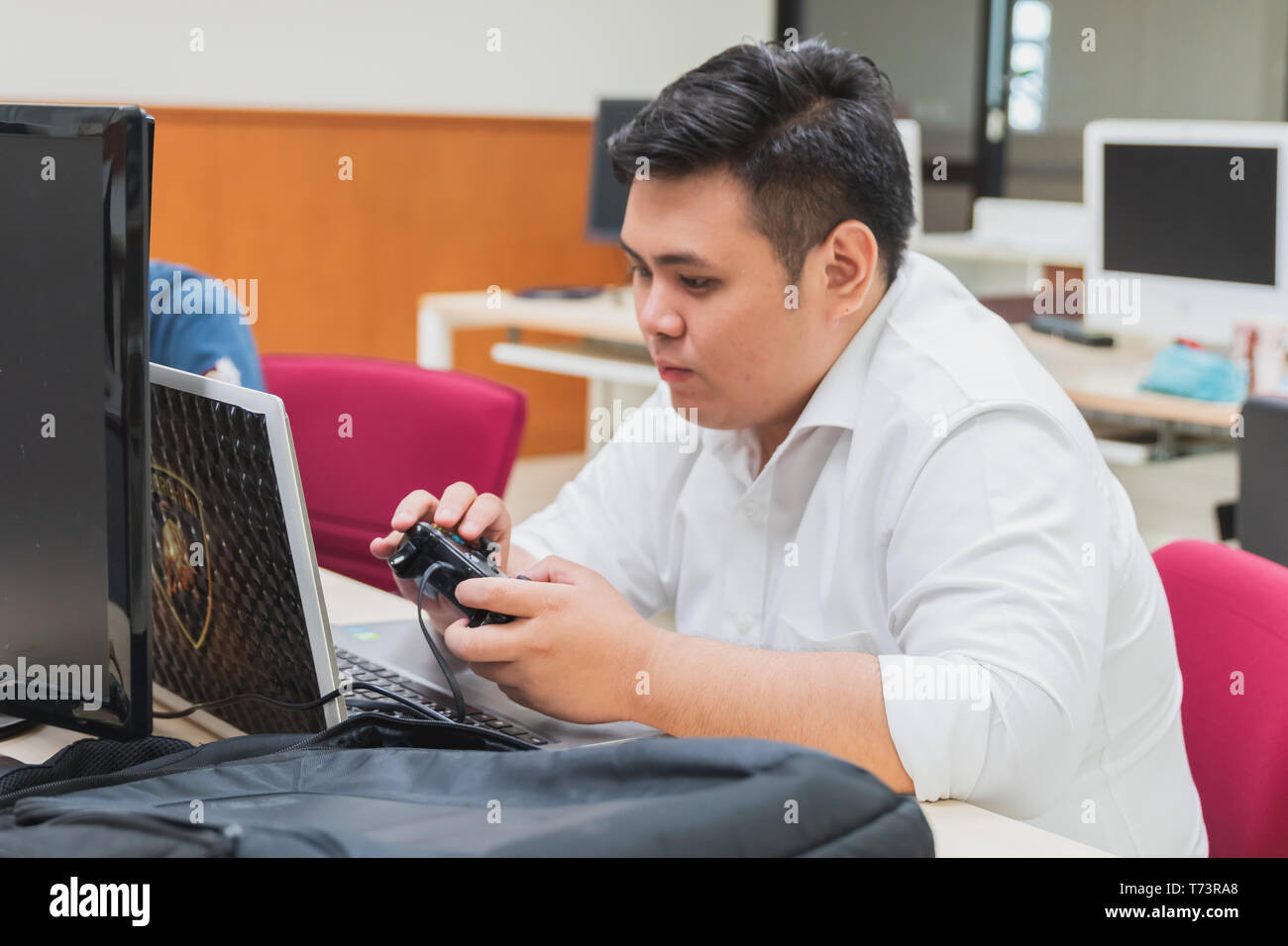 Asian University Student playing game on his laptop during a computer ...