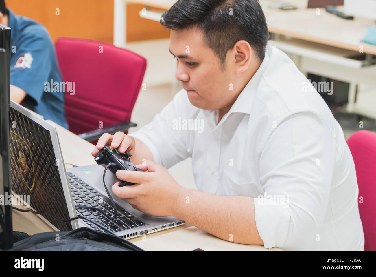 Asian University Student playing game on his laptop during a computer ...