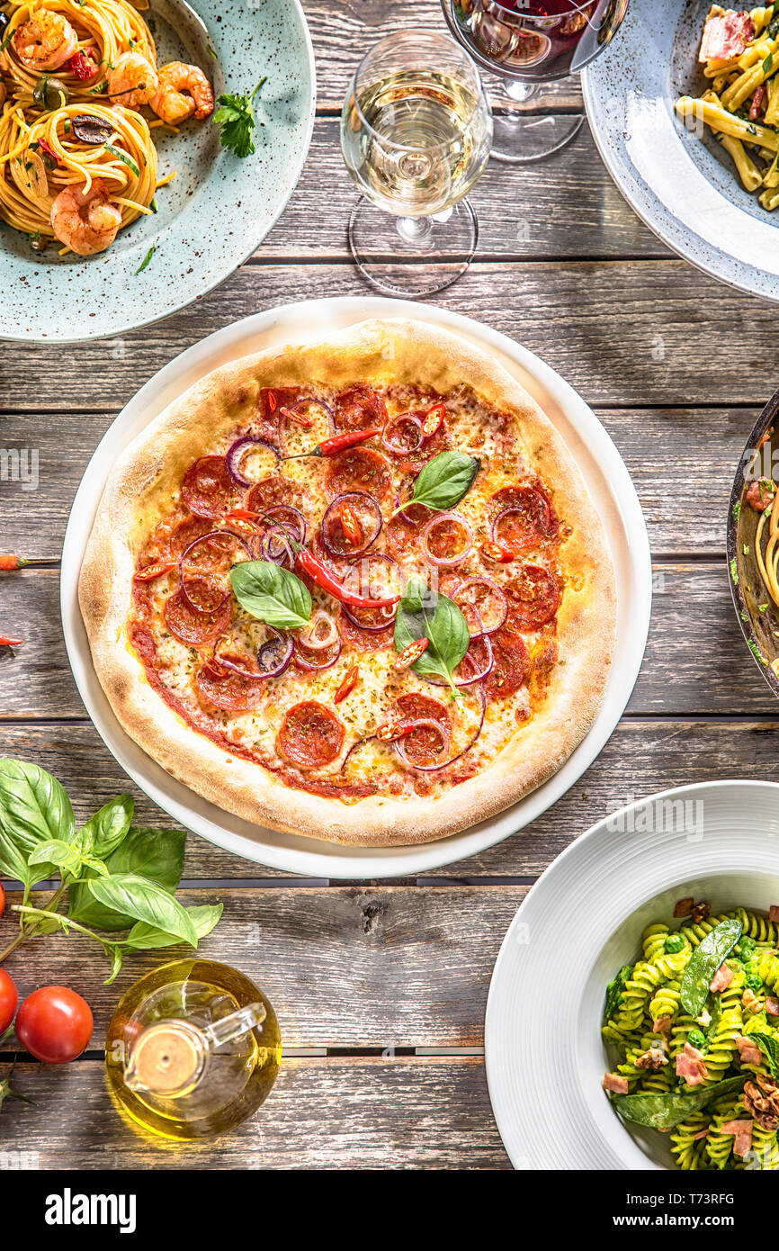 Top of view full table of italian meals on plates and pan. Pizza pasta ...