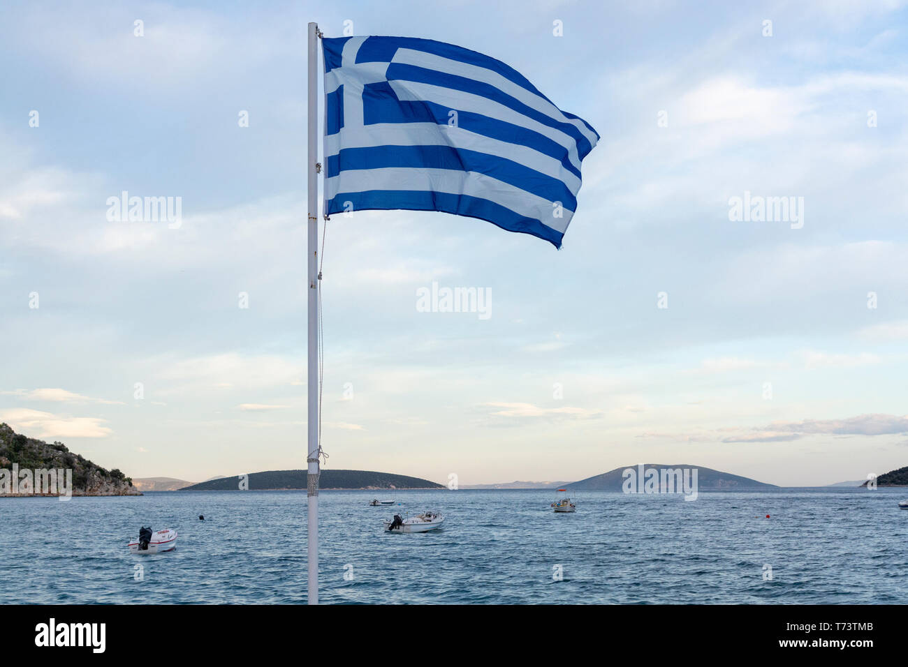 National symbol of Greece, blue-white greek flag on flagpole, sea water ...