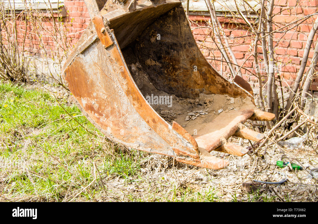 Old, rusty and dirty excavator bucket closeup on brick wall background ...