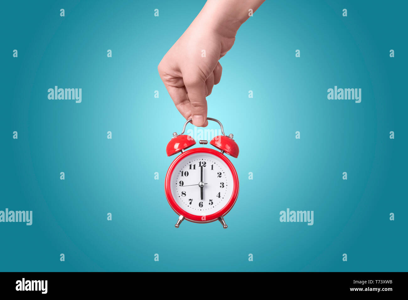 red alarm clock in hand, over blue background, concept time to get up ...