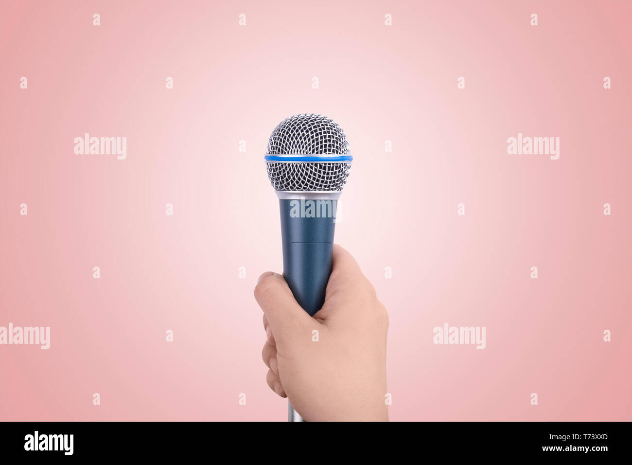microphone in hand over peach background Stock Photo - Alamy