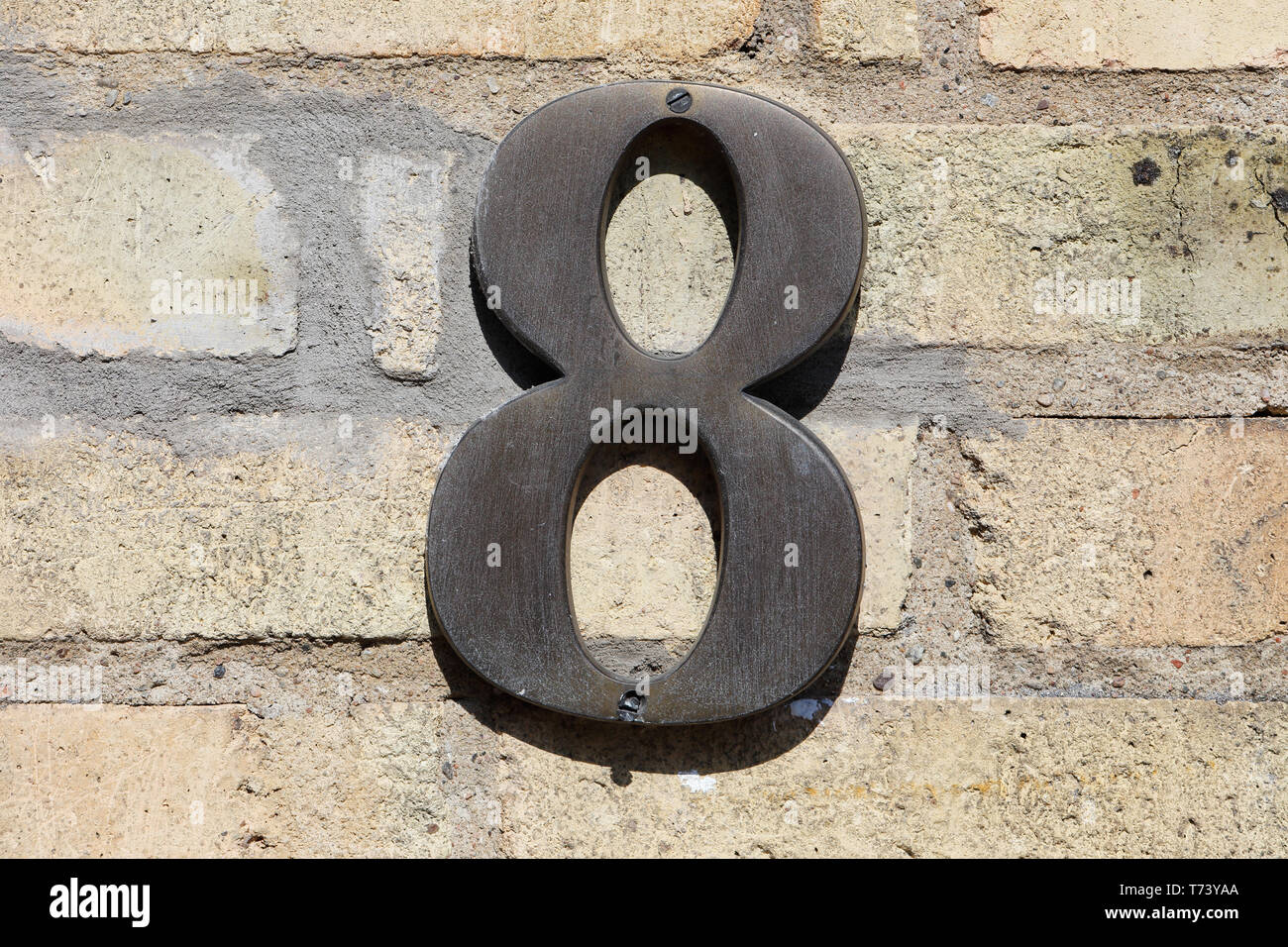 House number eight on a yellow brick wall Stock Photo - Alamy
