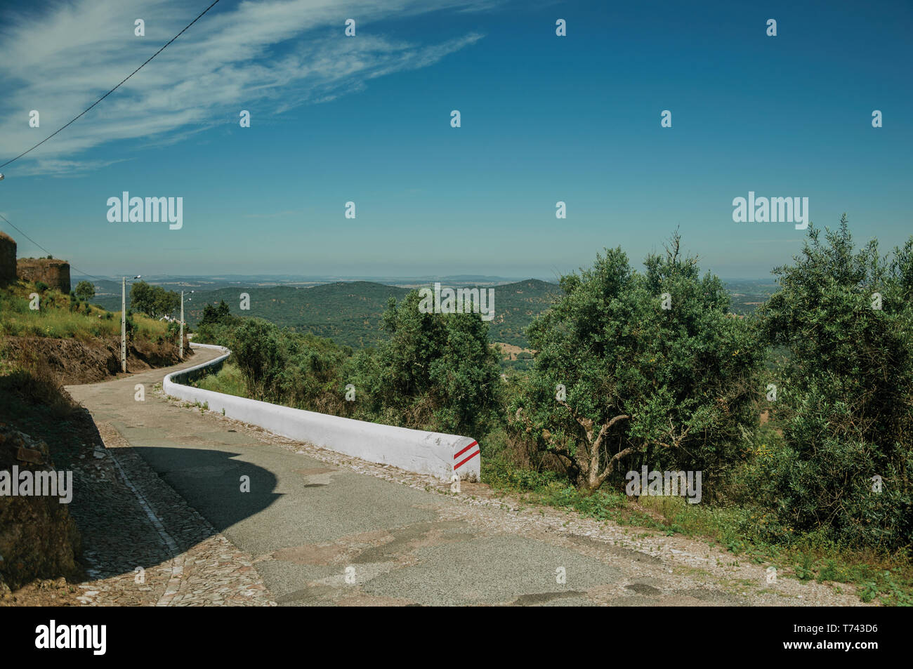 Road with curves and stone guard rail on slope in a countryside ...