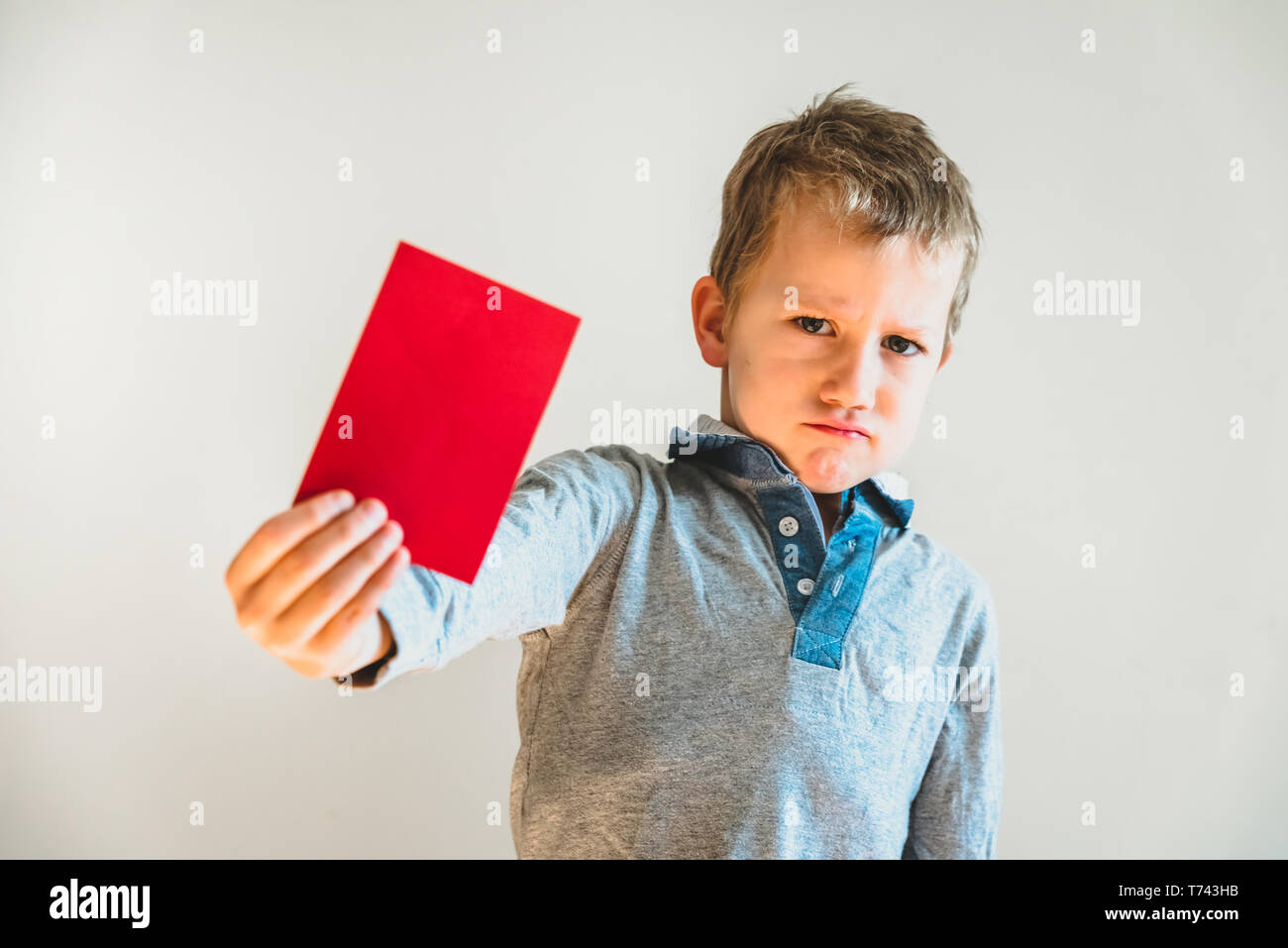 Angry face child showing a red card as a warning, stop bullying concept ...
