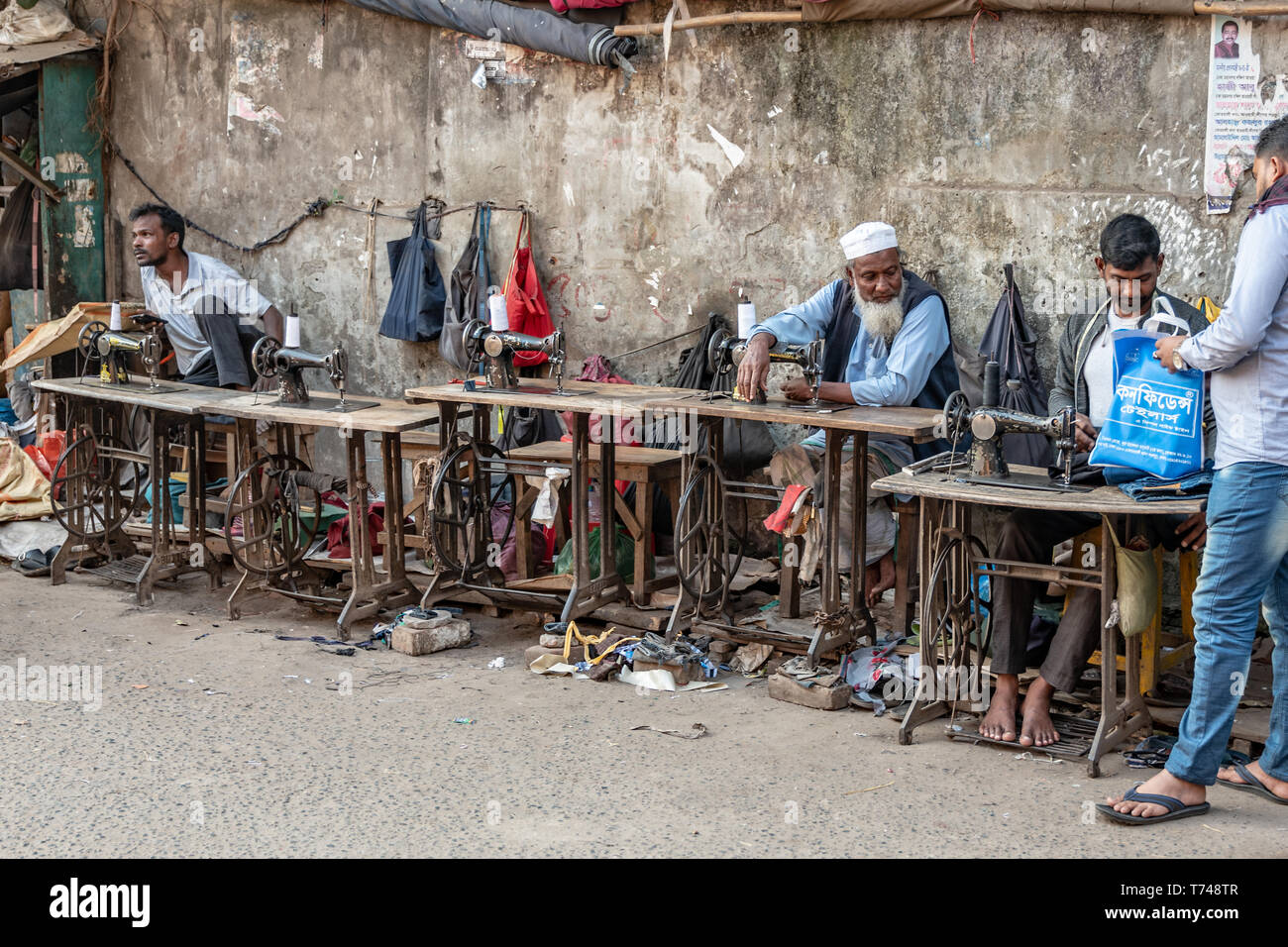 Men operating sewing machines to mend clothing on the street in old ...