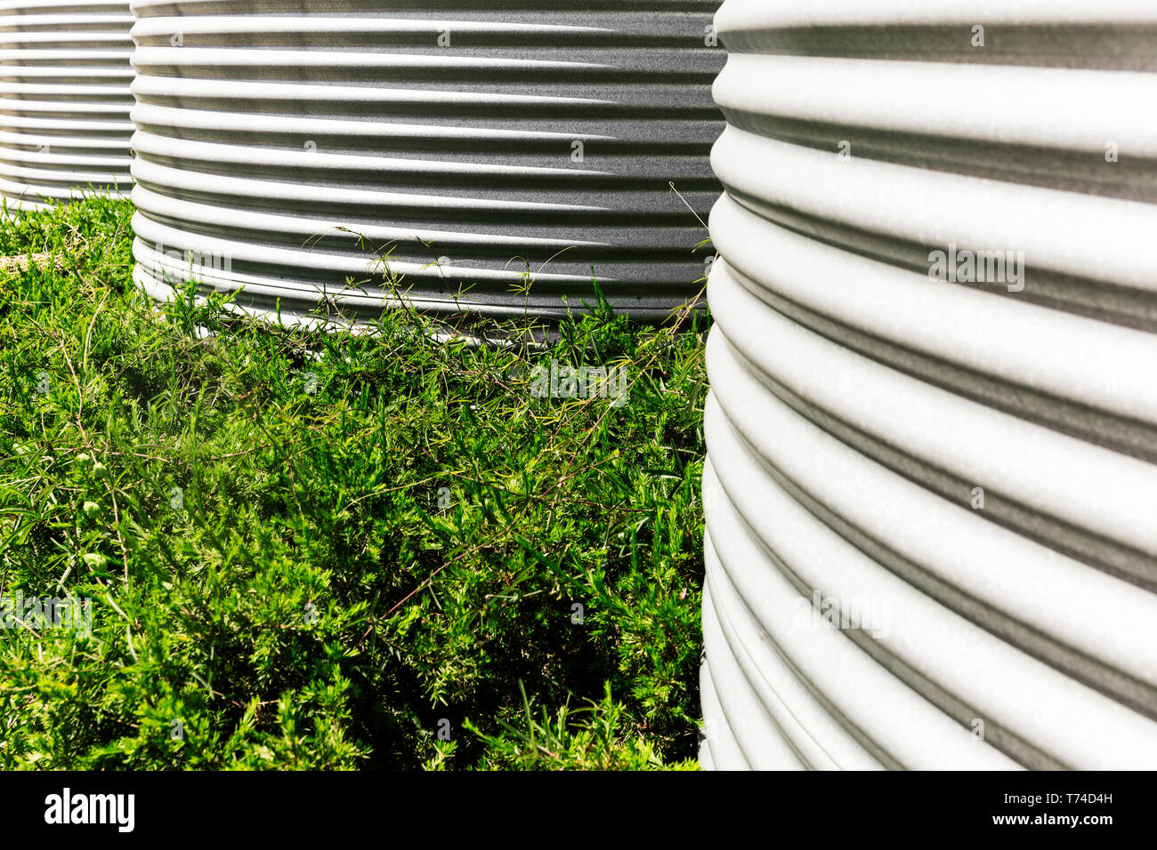Large water collection tanks beside lush green bush Stock Photo - Alamy
