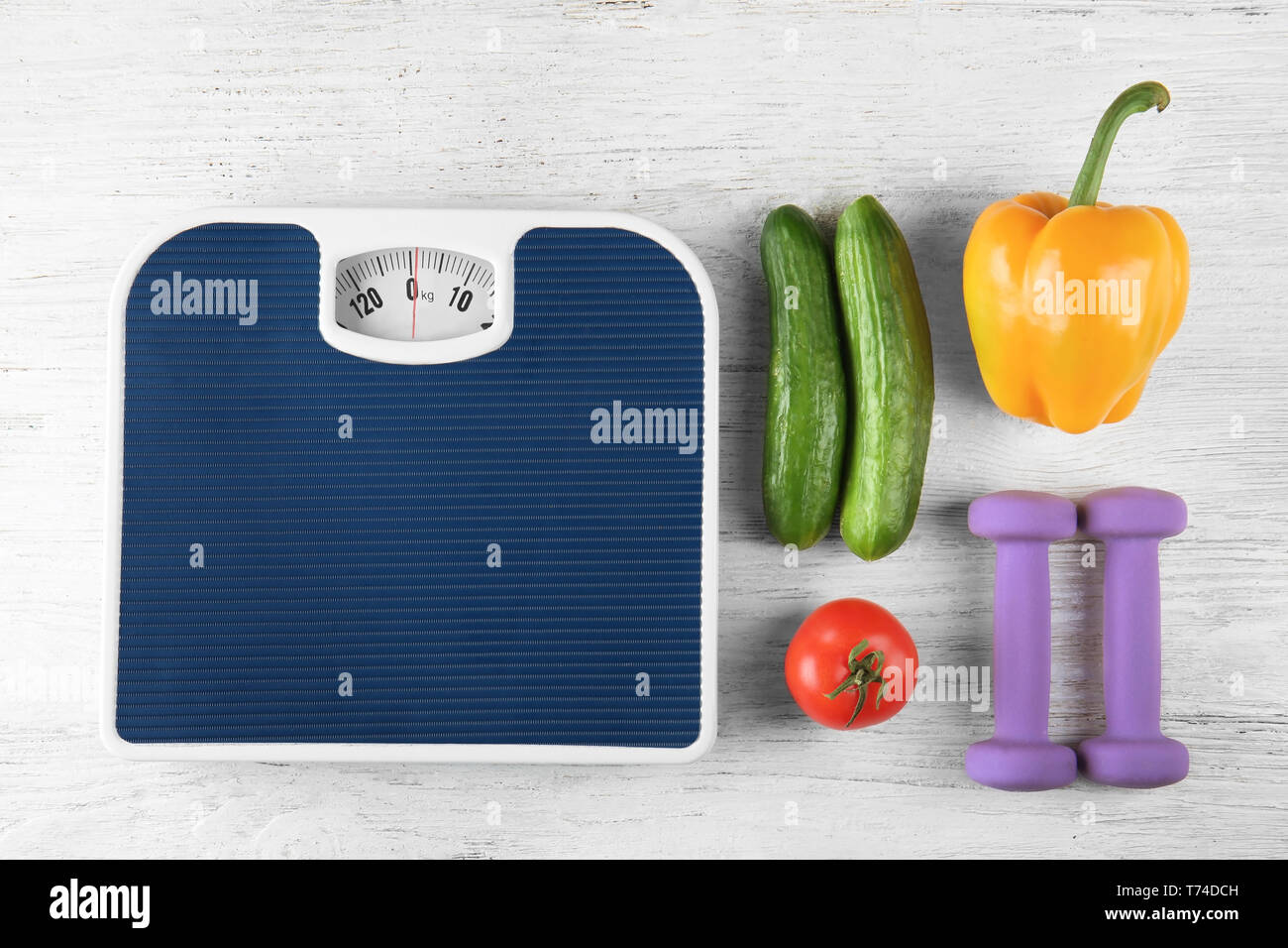 Fresh vegetables, dumbbells and scales on wooden background. Healthy ...