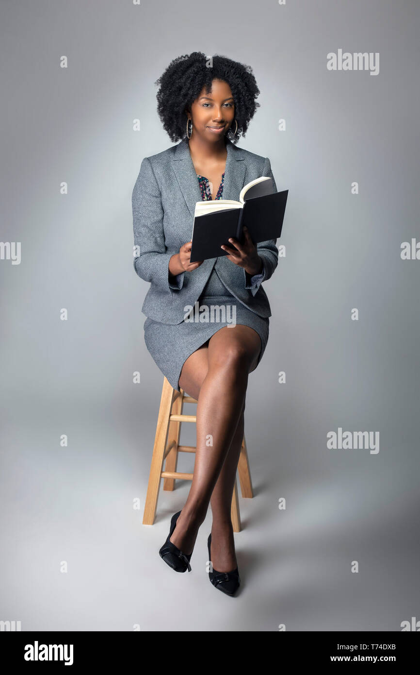 Black female author posing with a book in a studio for a portrait. She ...