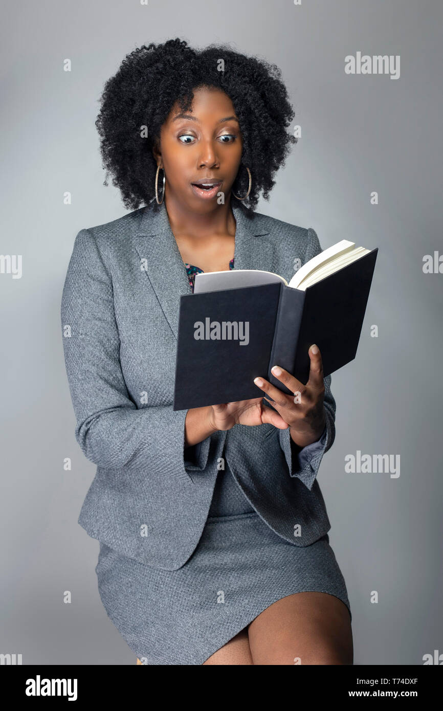 Black female author posing with a book in a studio for a portrait. She ...
