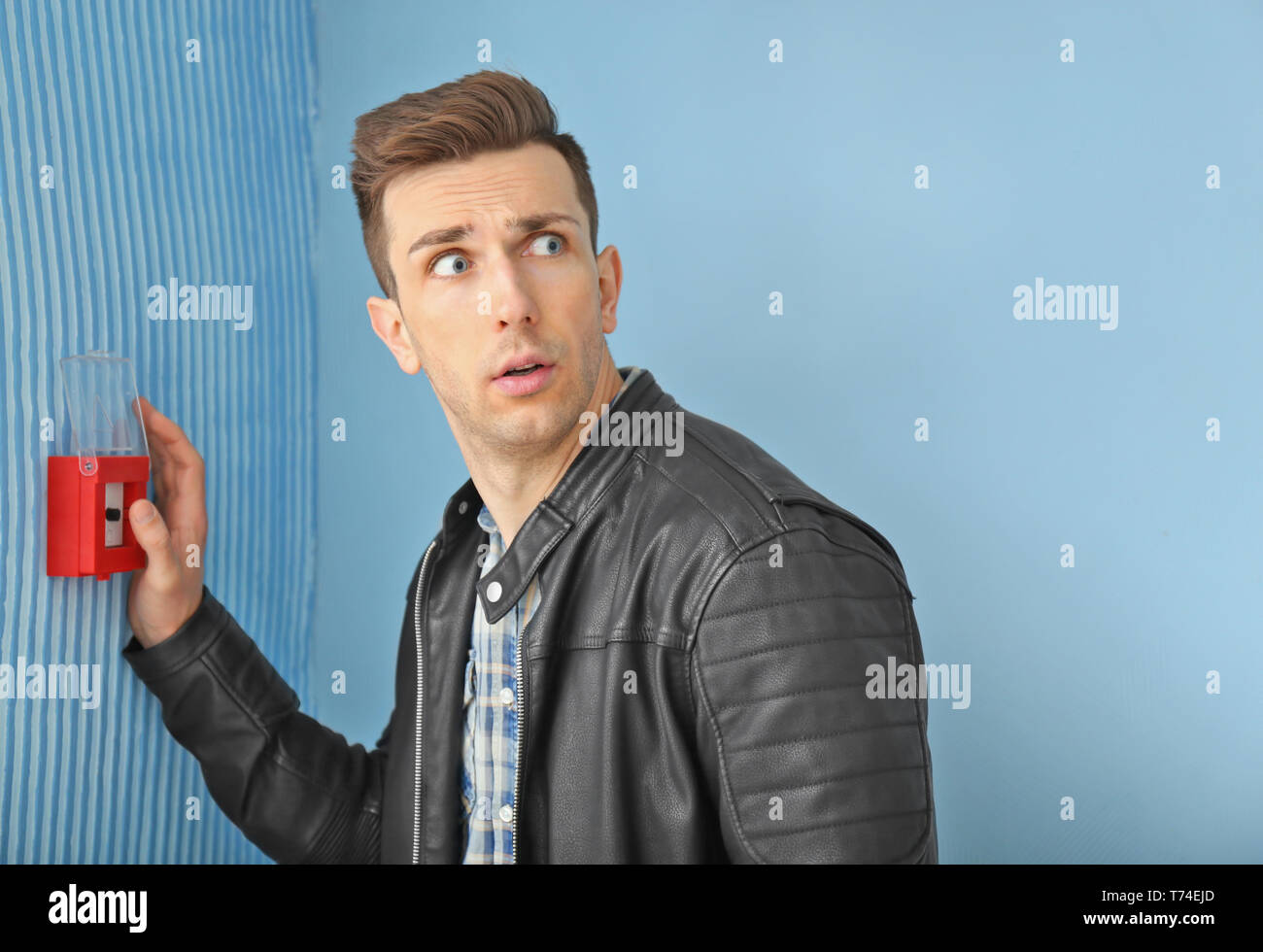 Frightened man using fire alarm system indoors Stock Photo - Alamy