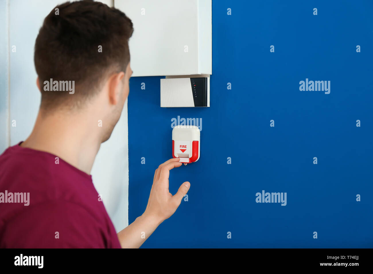 Young man using fire alarm system indoors Stock Photo - Alamy