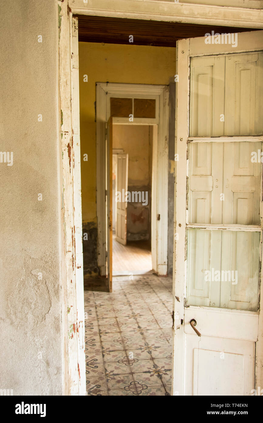 An old worn door open into an empty room with antique ceramic tile ...