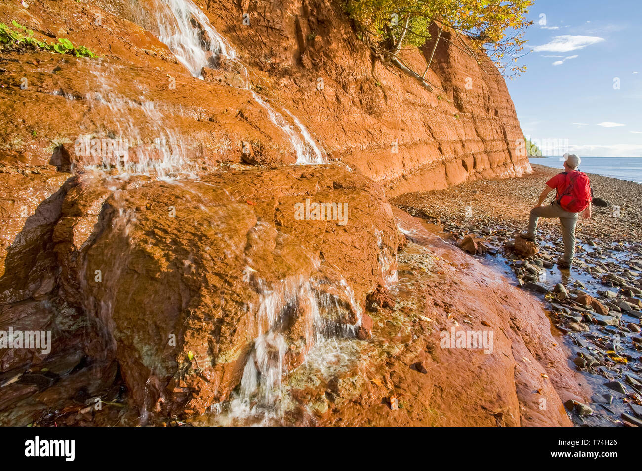 Hiking at low tide beside the sandstone cliffs, Cape Blomidon ...