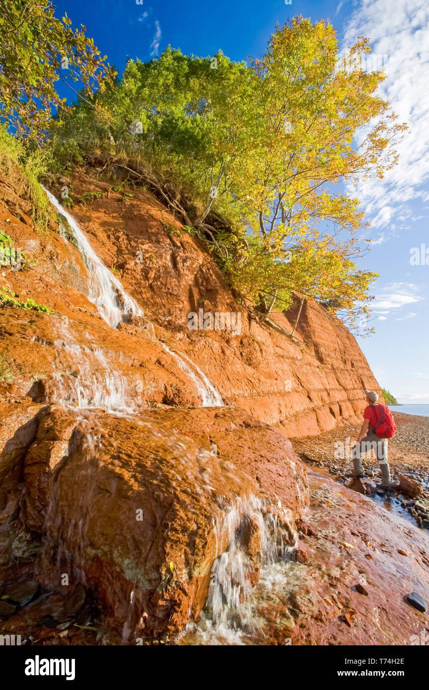 Hiking at low tide beside the sandstone cliffs, Cape Blomidon ...