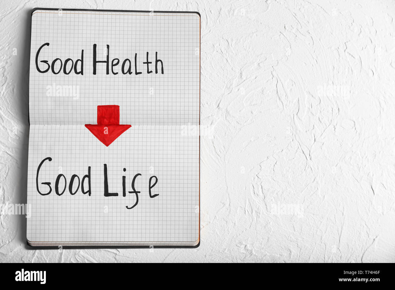 Phrase "Good health - good life" written in notebook on white ...