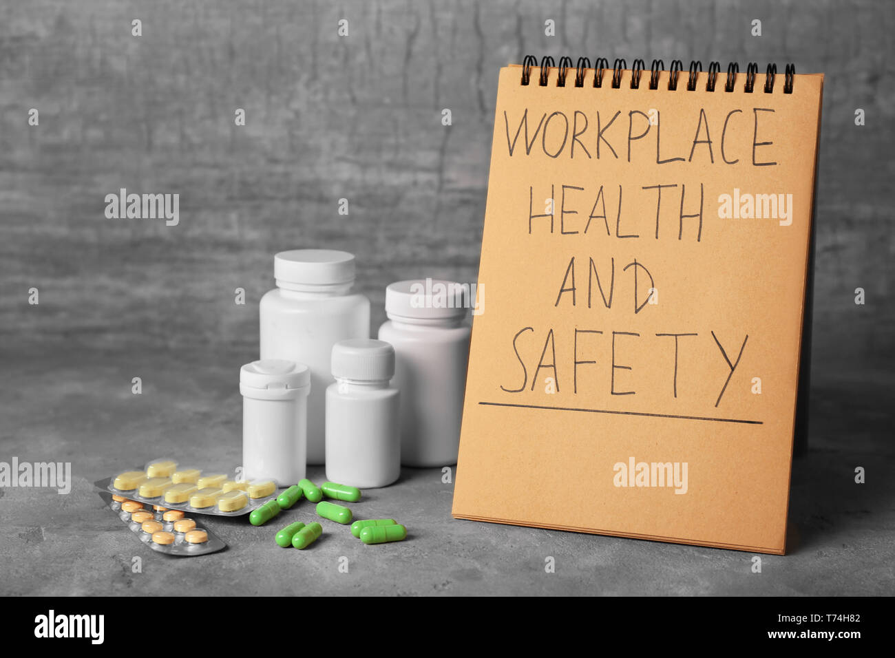 Words "Workplace, health and safety" written in notebook and pills on ...
