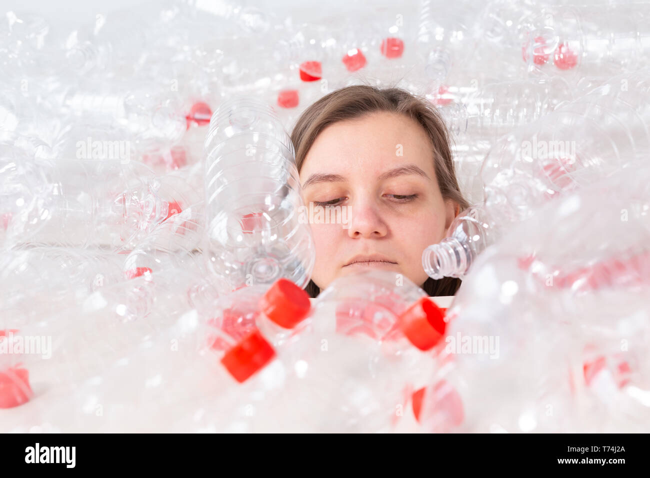 Dehydrated sick woman is lying in a pile of plastic bottles ...