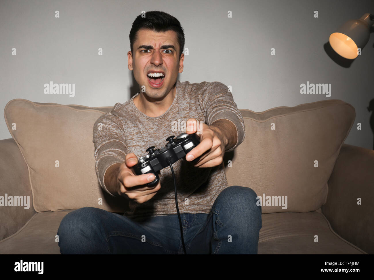 Young man playing video game at home in the evening Stock Photo - Alamy