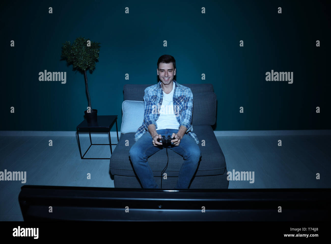 Young man playing video game at home in the evening Stock Photo - Alamy