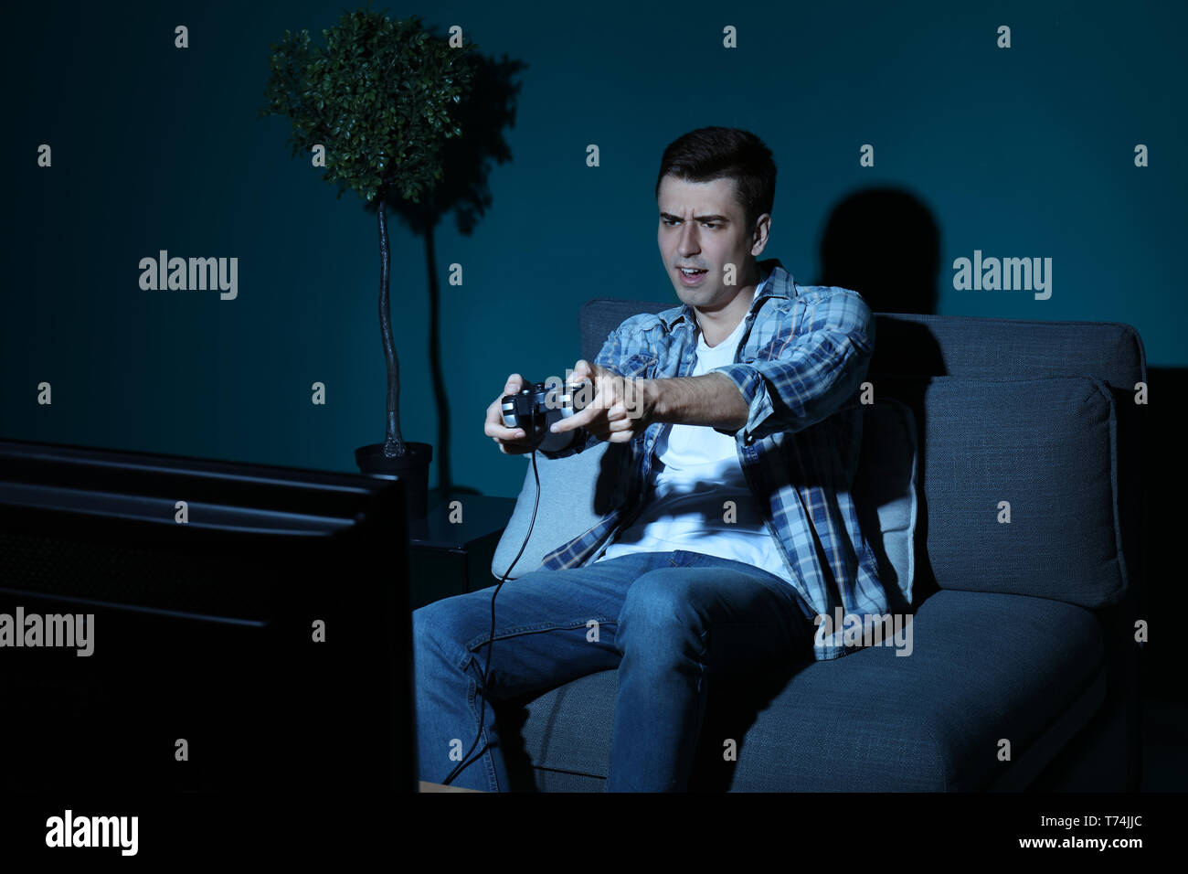 Young man playing video game at home in the evening Stock Photo - Alamy