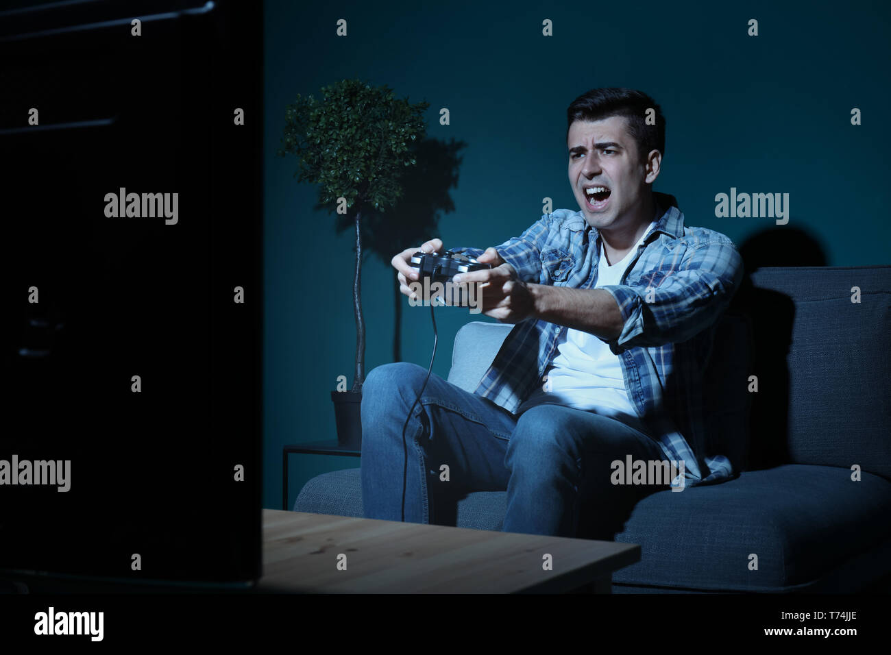 Young man playing video game at home in the evening Stock Photo - Alamy